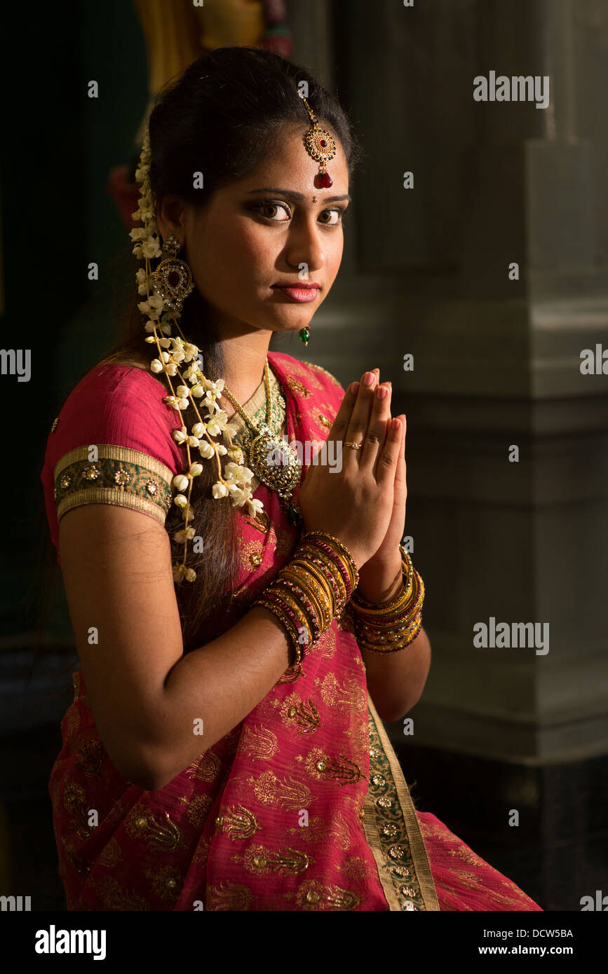 Young Indian female in traditional sari dress praying in a hindu temple ...