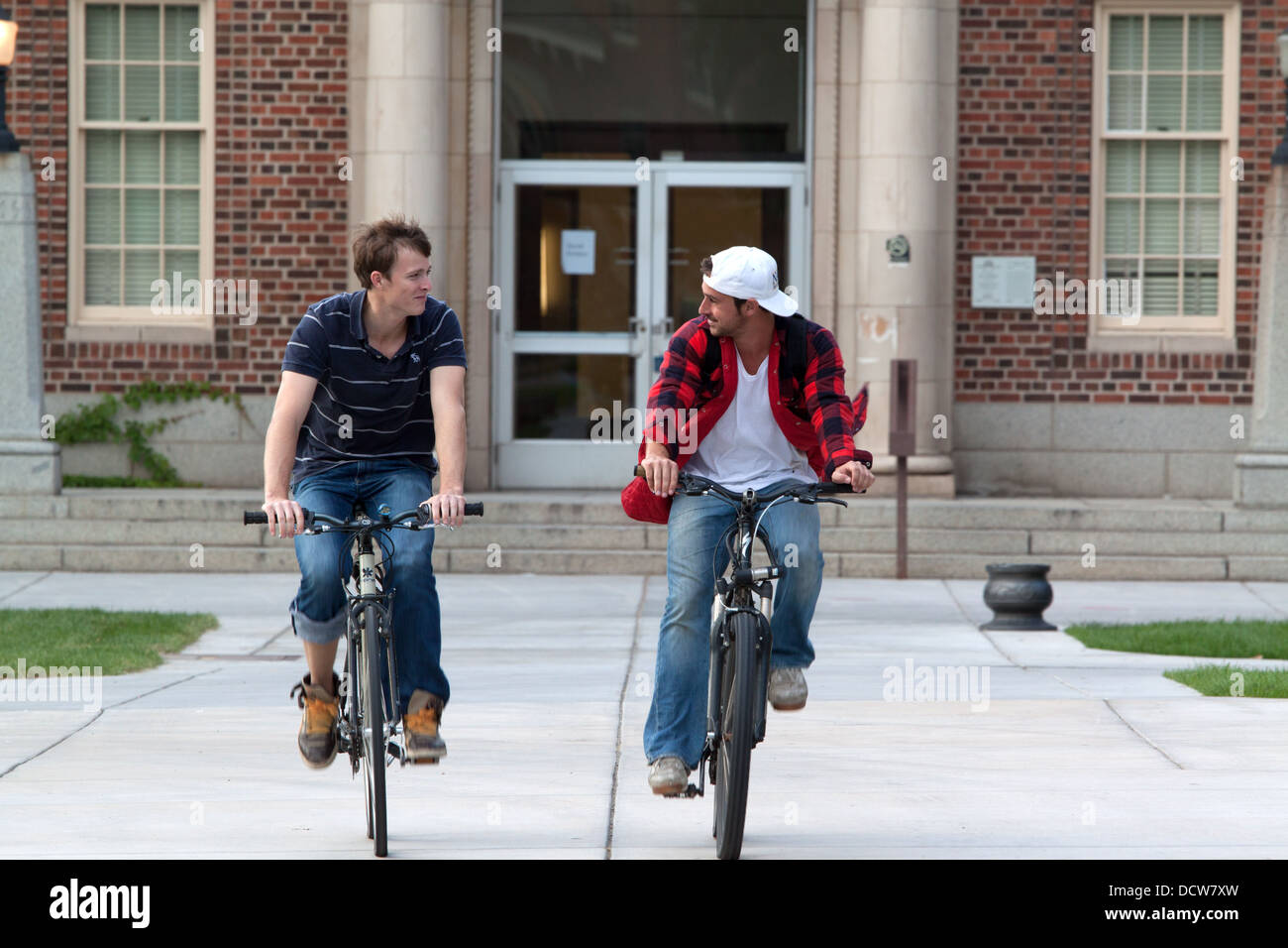 Two young men riding bicycles on a sidewalk at a college Stock Photo ...