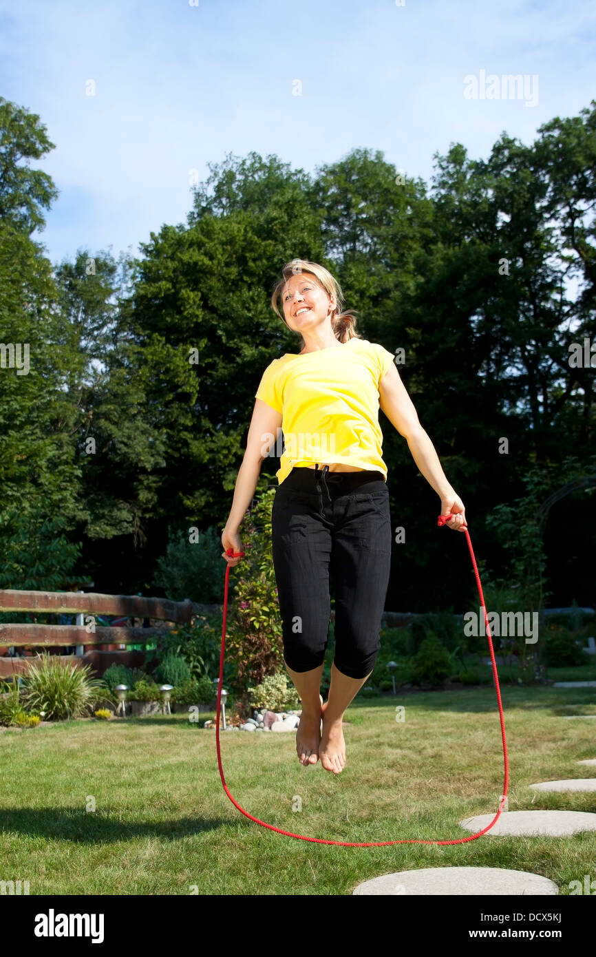 pretty woman jumping rope in the garden Stock Photo - Alamy