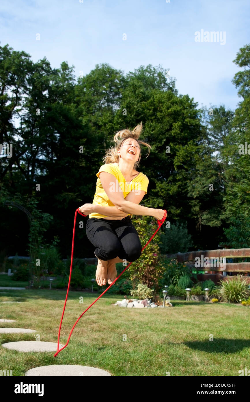 Athletic blond woman jumping rope in the garden Stock Photo - Alamy