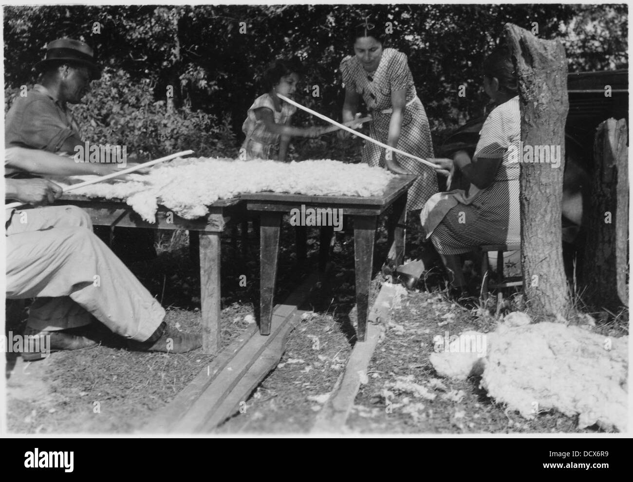Four adults are working around a table outdoors, likely engaged in a ...