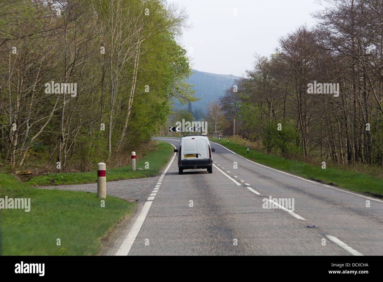 A van in front on a highway in Scotland with the road curving ahead ...