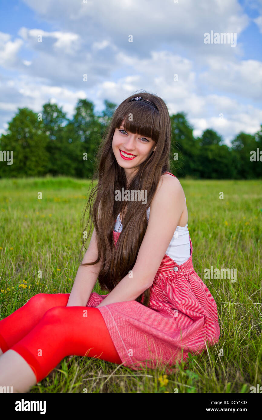 Pretty girl in red sarafan lies on the green grass Stock Photo - Alamy