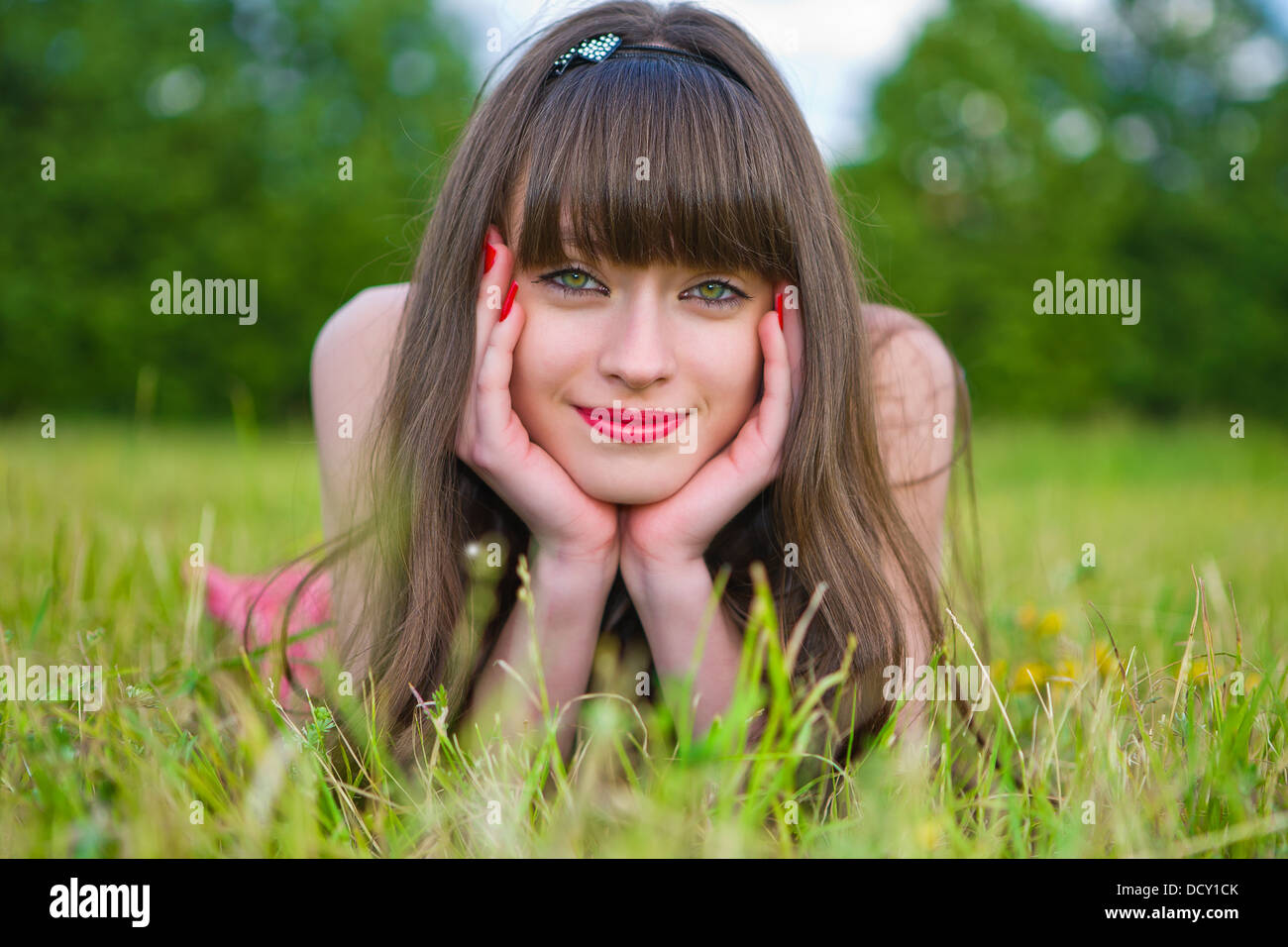 Pretty girl in red sarafan lies on the green grass Stock Photo - Alamy