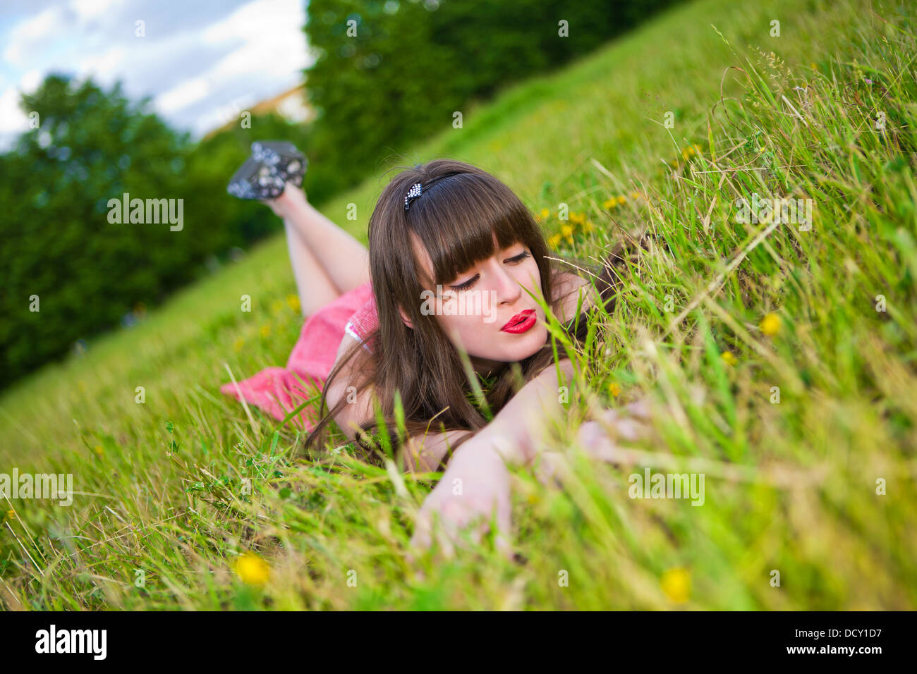 Pretty girl in red sarafan lies on the green grass Stock Photo - Alamy
