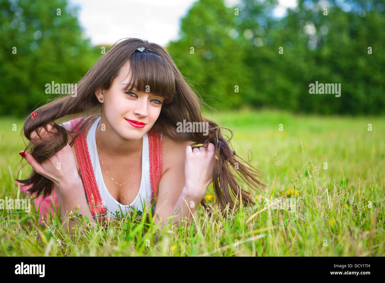 Pretty girl in red sarafan lies on the green grass Stock Photo - Alamy