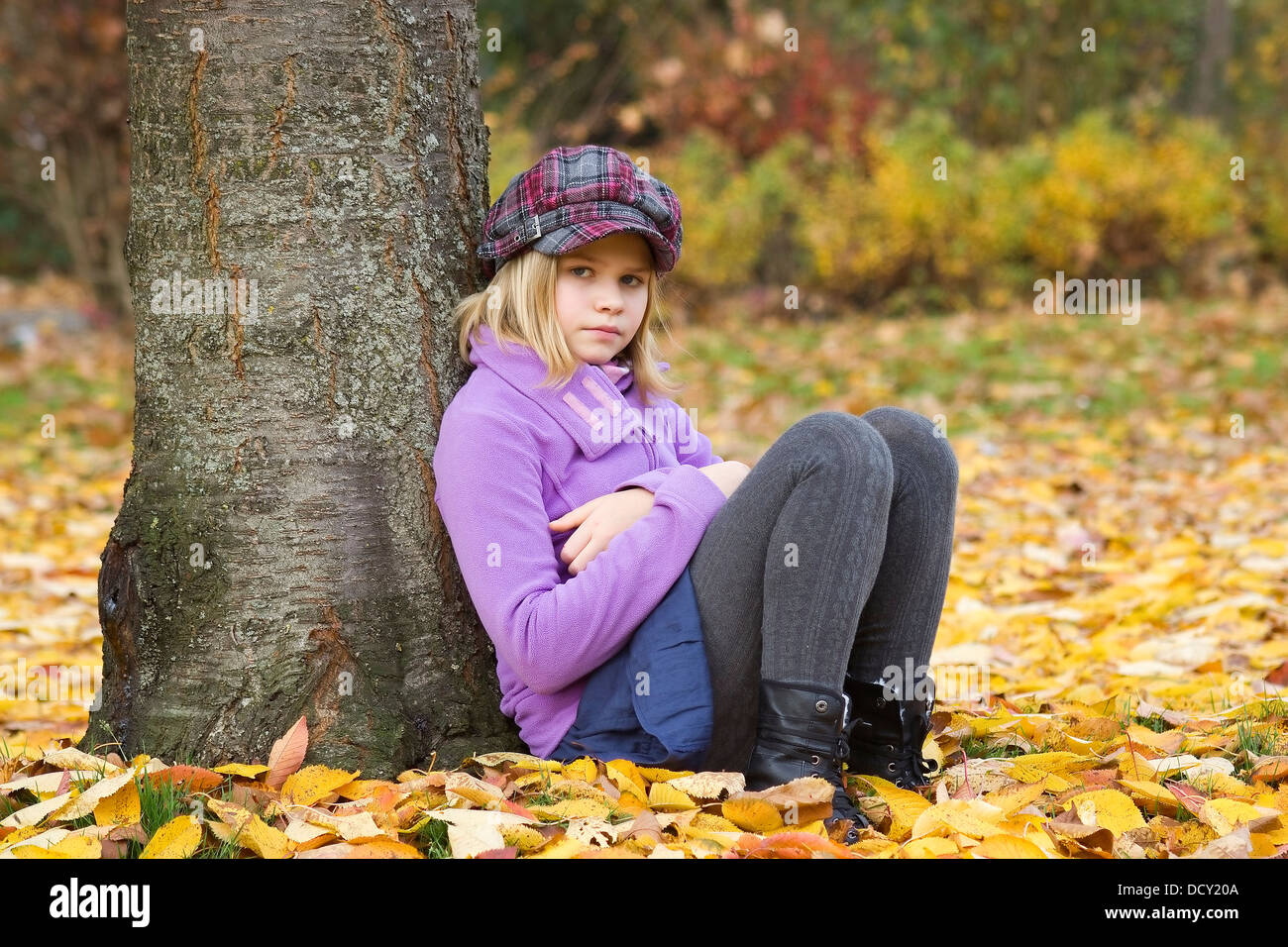 Full length portrait of a little girl sitting under tree in autu Stock ...