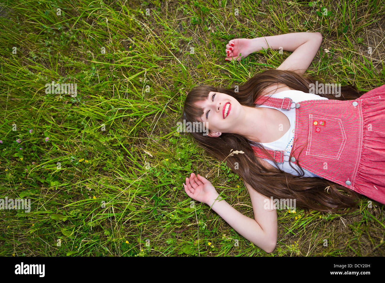 Pretty girl in red sarafan lies on the green grass Stock Photo - Alamy