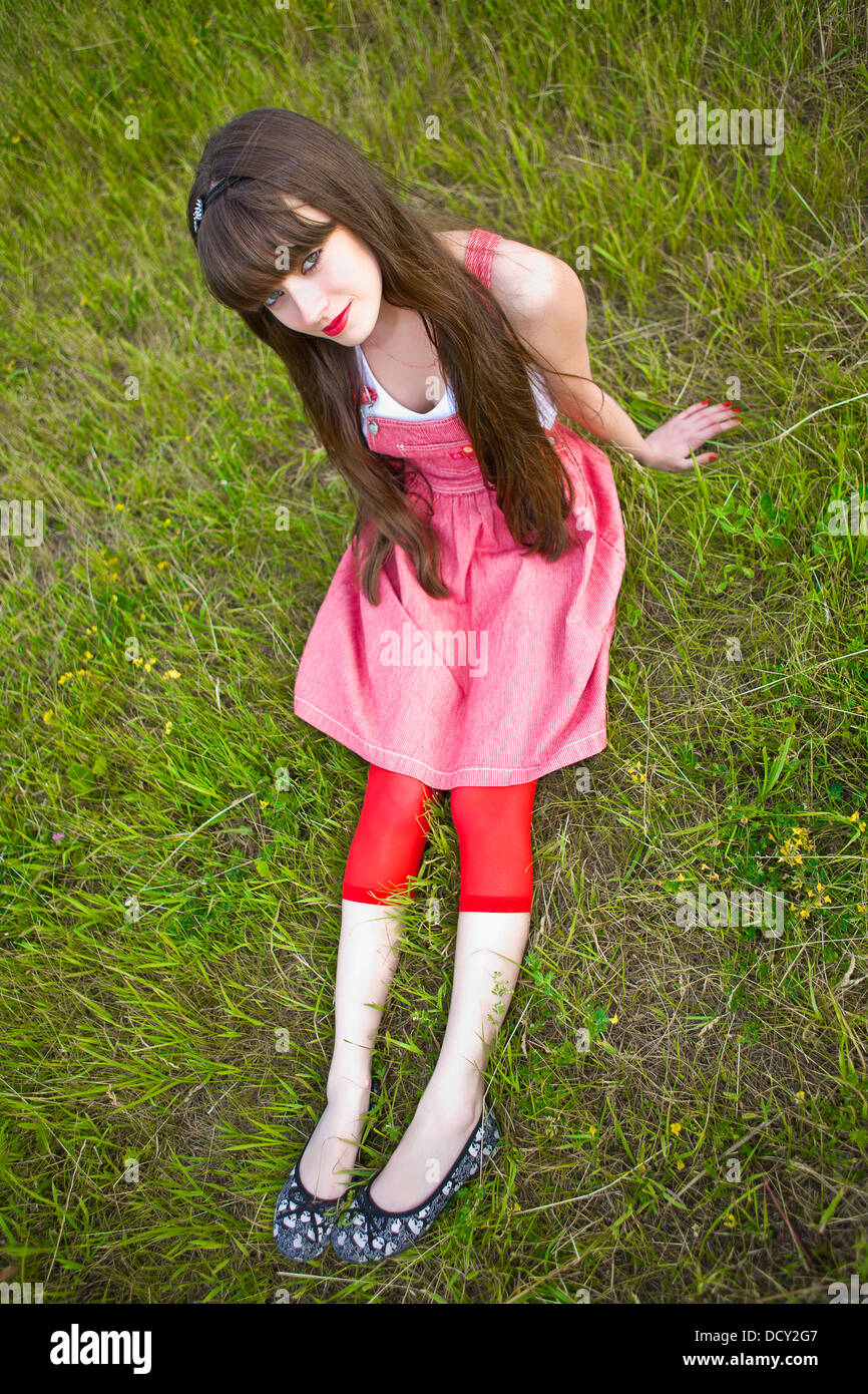 Pretty girl in red sarafan lies on the green grass Stock Photo - Alamy