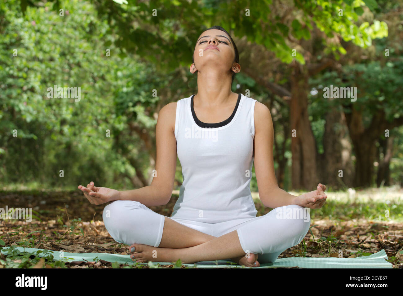 Young woman in lotus position meditating in a park Stock Photo - Alamy