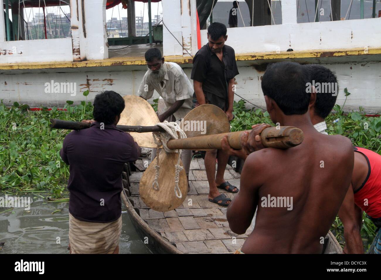 Bangladeshi laborers carry the propellor of a ferry being refurbished ...