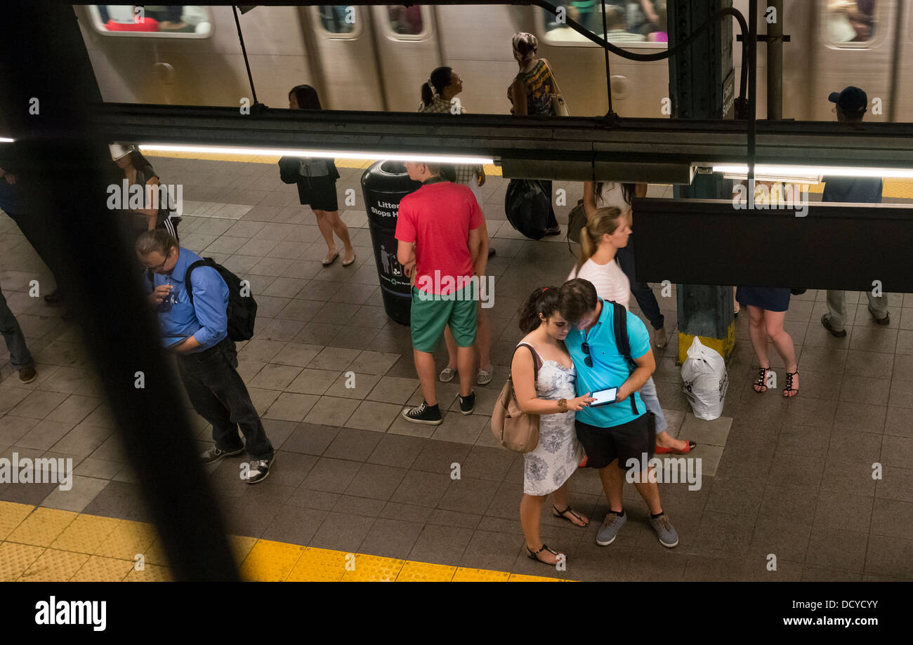 Couple on a New York City Subway platform looking at a digital tablet ...