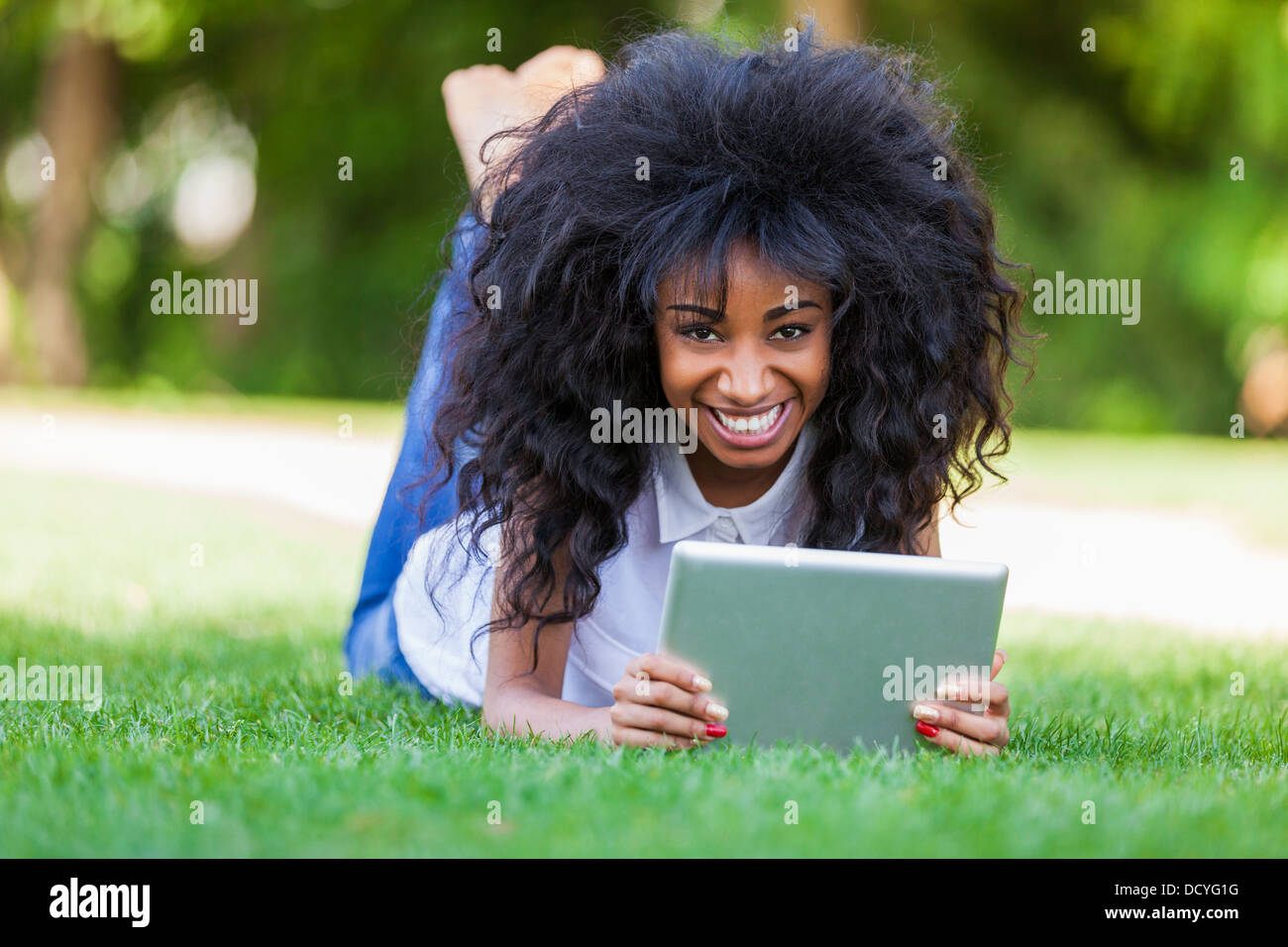 Outdoor portrait of a smiling teenage black girl using a tactile tablet ...