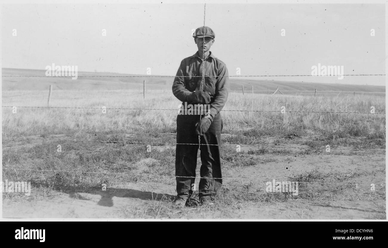 A man holds a survey rod next to a fence, likely conducting land ...