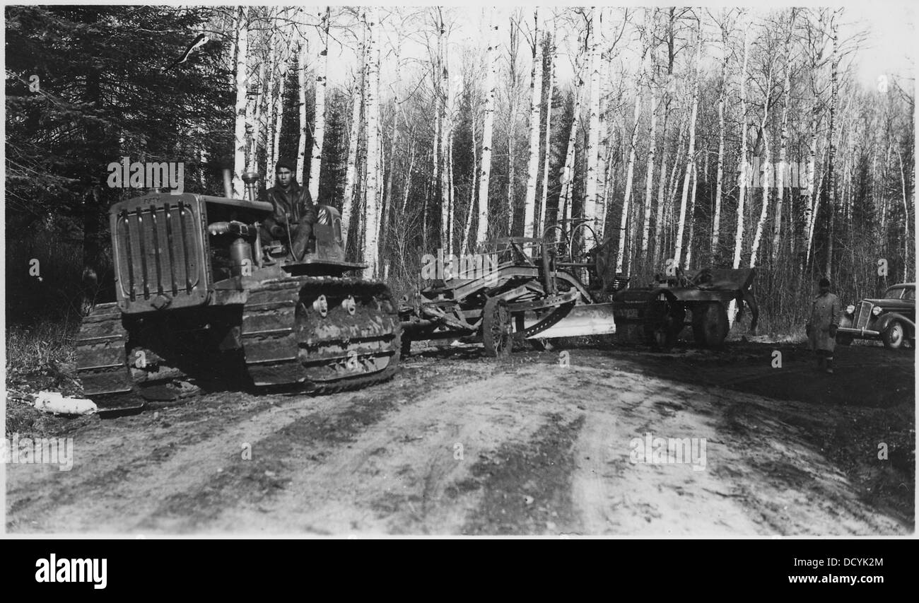 A man operating a tractor leads a line of road construction equipment ...