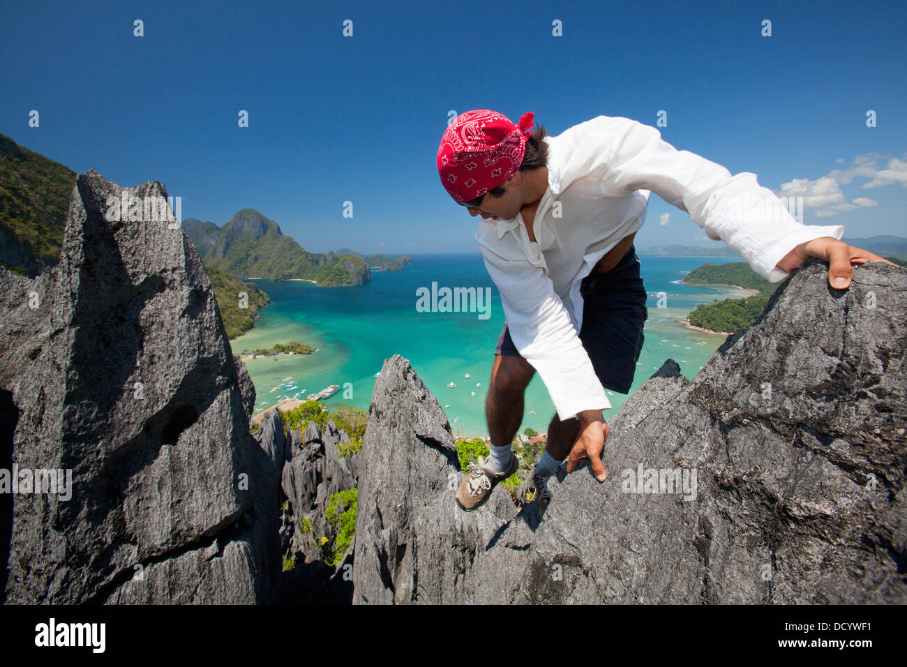 A Man Rock Climbs On Top Of Sharp Limestone Spires Overlooking The ...