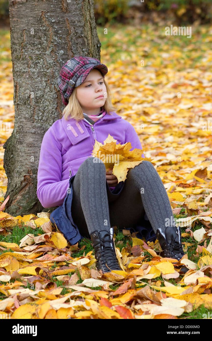 Full length portrait of a little girl sitting under tree in autu Stock ...