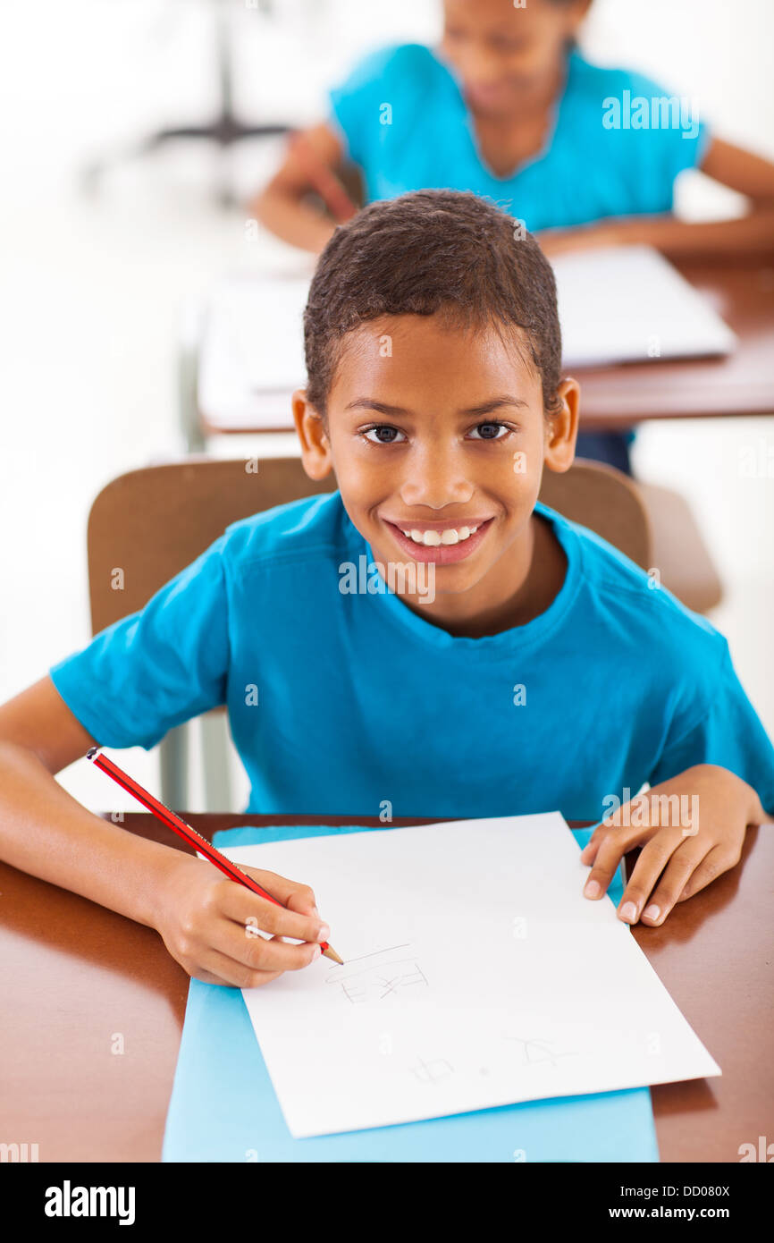 cheerful african schoolboy writing classwork in classroom Stock Photo ...
