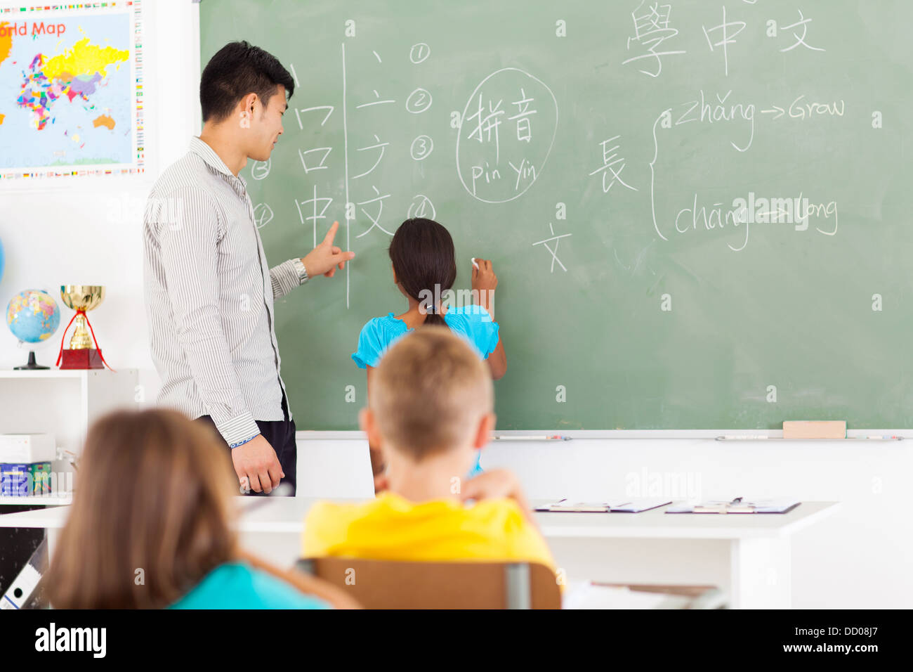 elementary school student writing answer on the board with teacher ...