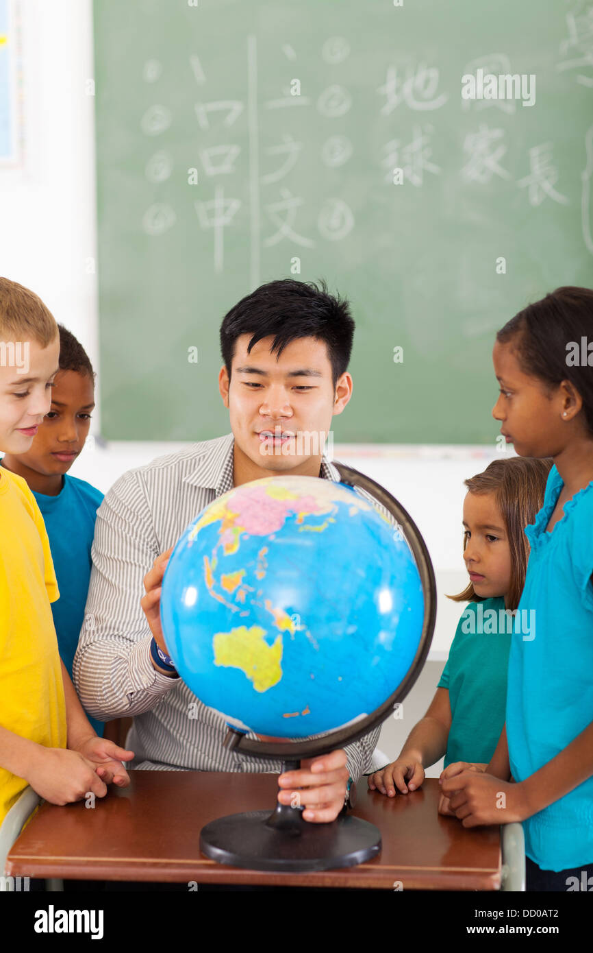 group elementary school students and teacher looking at globe in ...