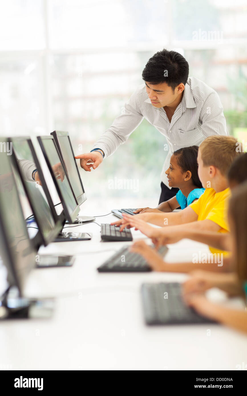 primary school teacher helping student in computer room Stock Photo - Alamy