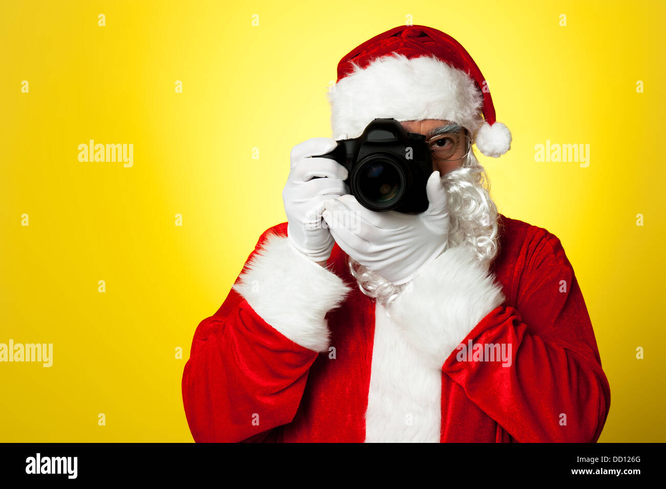 Say cheese! Santa capturing a perfect moment. Isolated over yellow ...