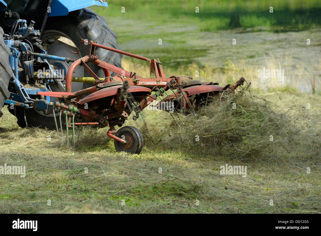 A Pottinger Kombi 401 Hay Tedder working on the back of a farm tractor ...
