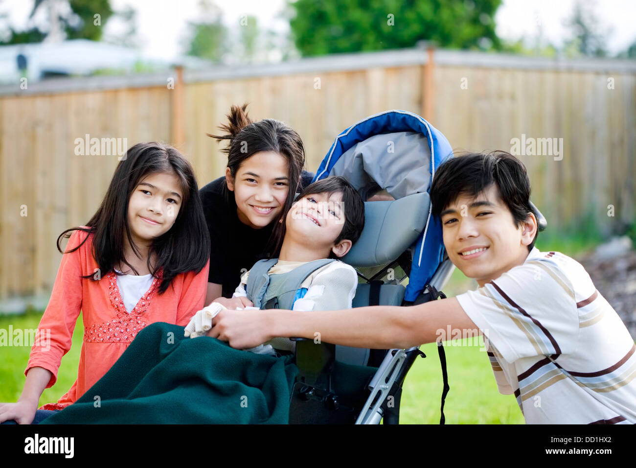 Three children surrounding a small disabled child in wheelchair Stock ...