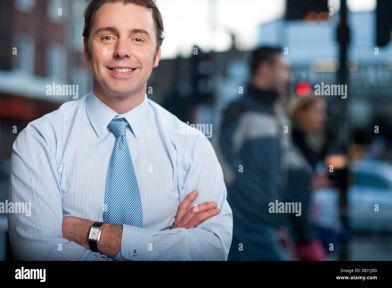 Friendly corporate guy posing with arms crossed. Street background ...