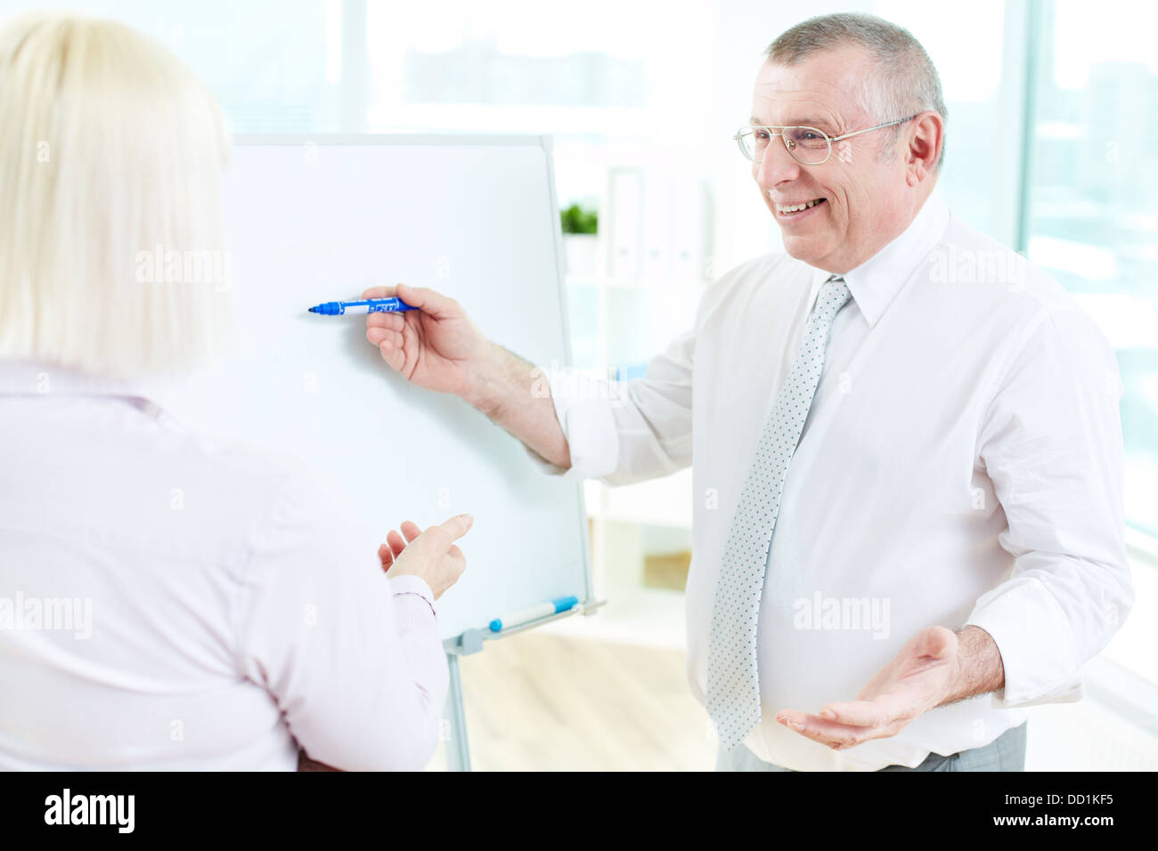 Image of mature businessman teaching his partner on whiteboard at ...
