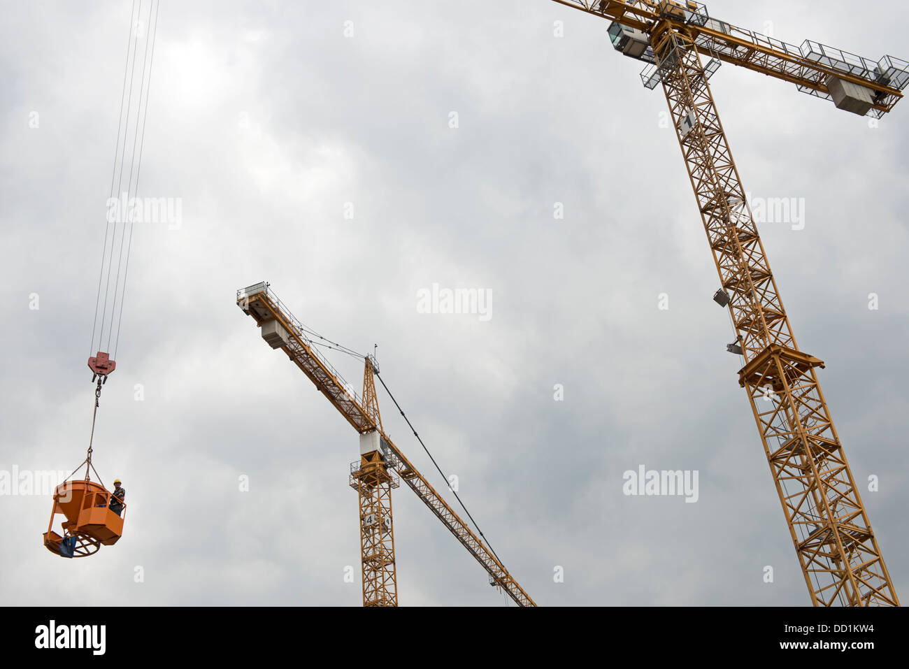 A bucket loaded with concrete being lifted into position by tower crane ...