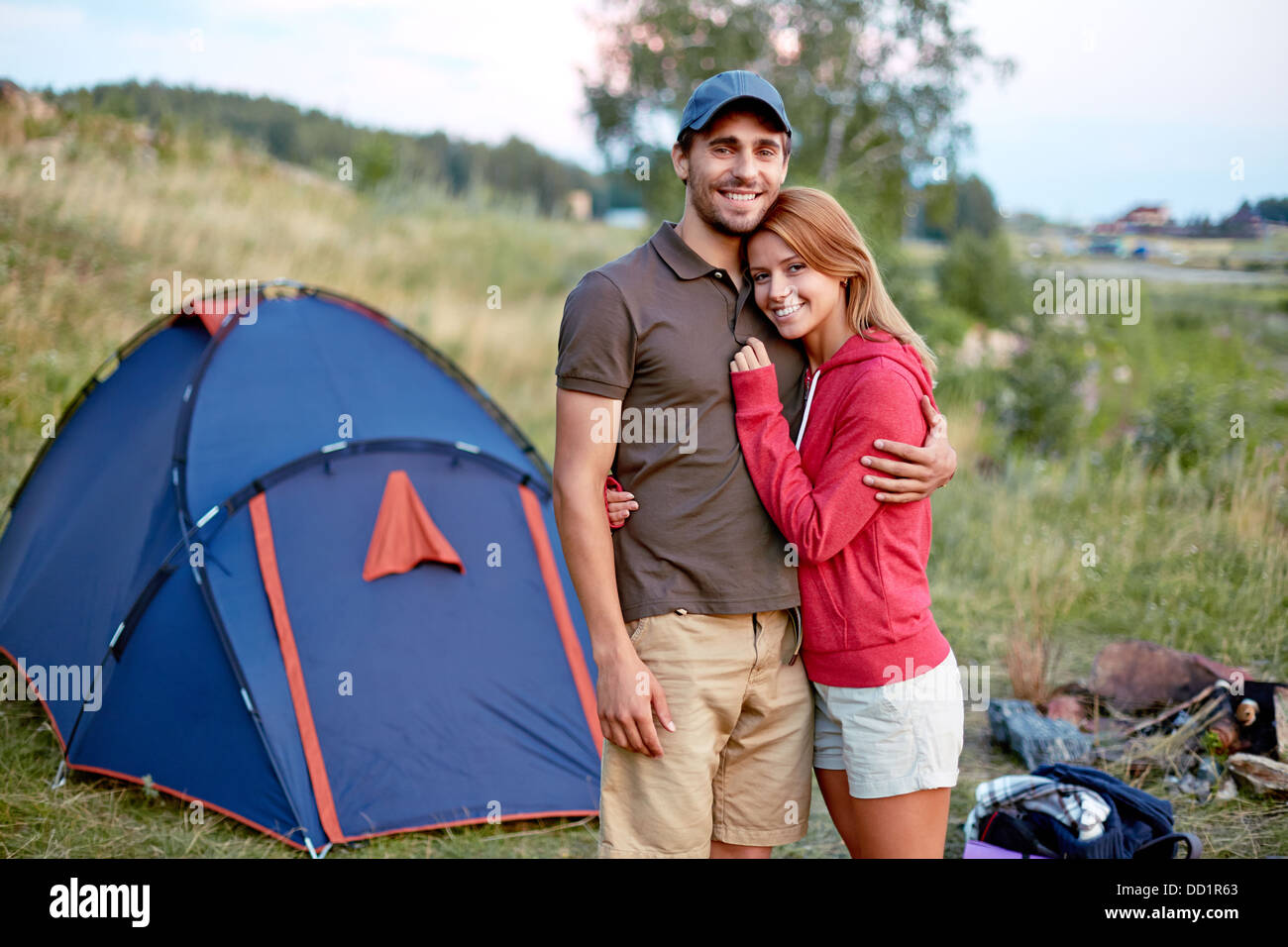 Photo of resting couple looking at camera in the countryside with tent ...
