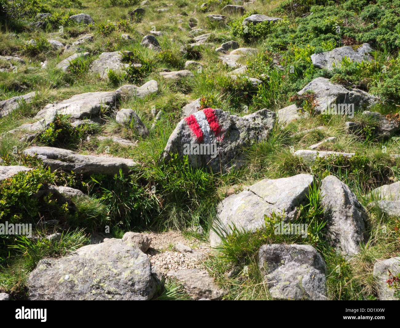A red and white painted rock marks out a hiking path in the mountains ...