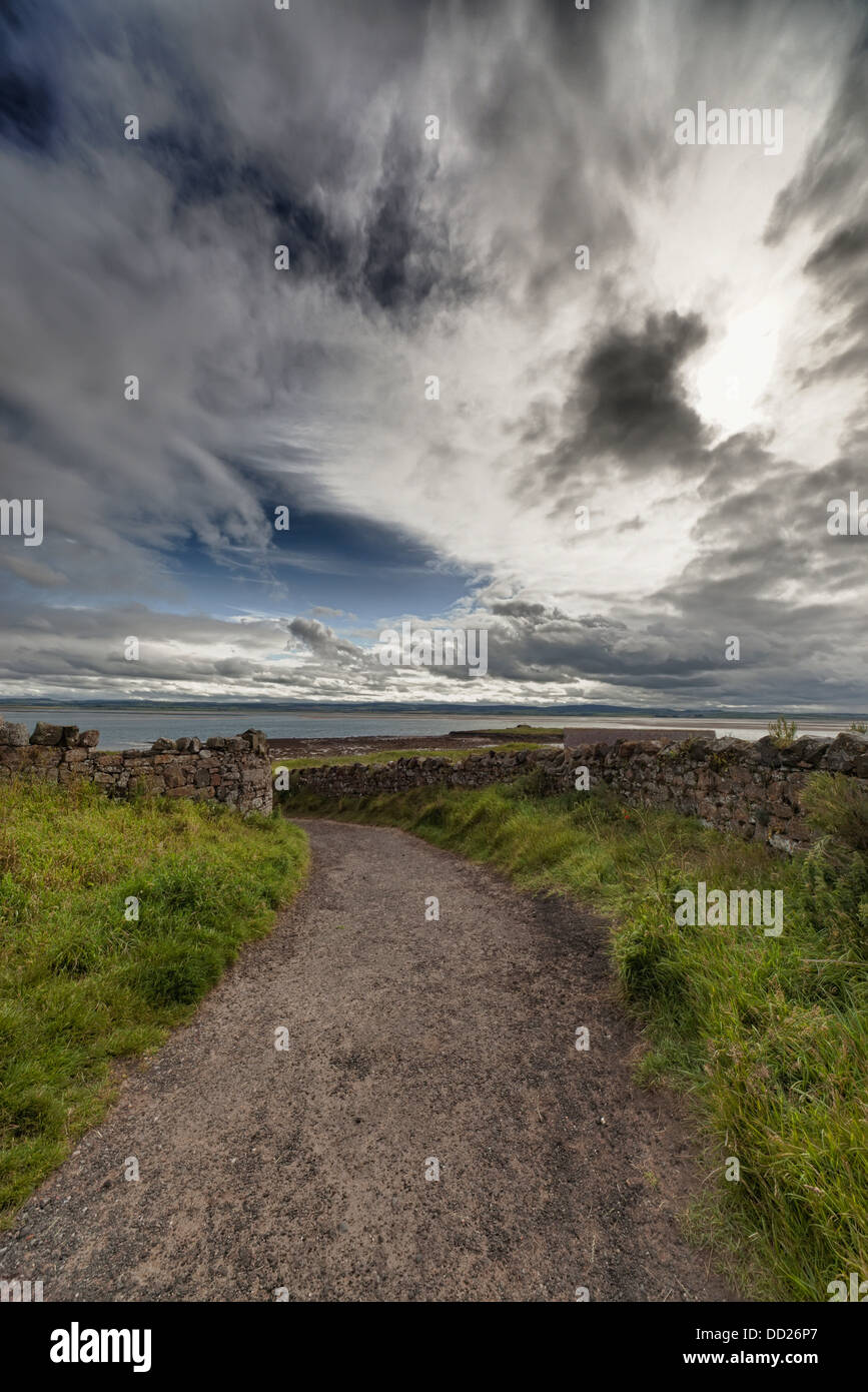 A Gravel Path Leading To The Coast Under A Cloudy Sky; Lindisfarne ...