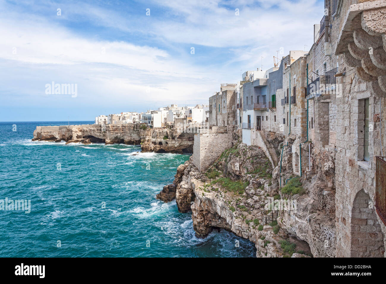Whitewashed buildings built on the cliff edge above sea caves ...