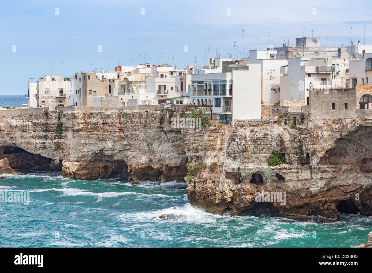 Whitewashed buildings built on the cliff edge above sea caves ...