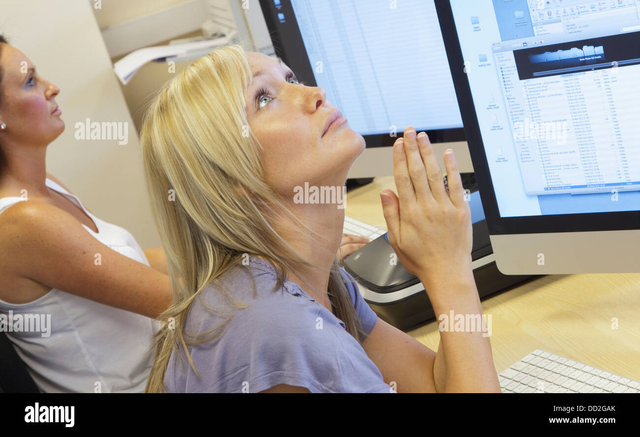 A Young Woman Sits At Her Computer At Work And Looks Up With Praying ...