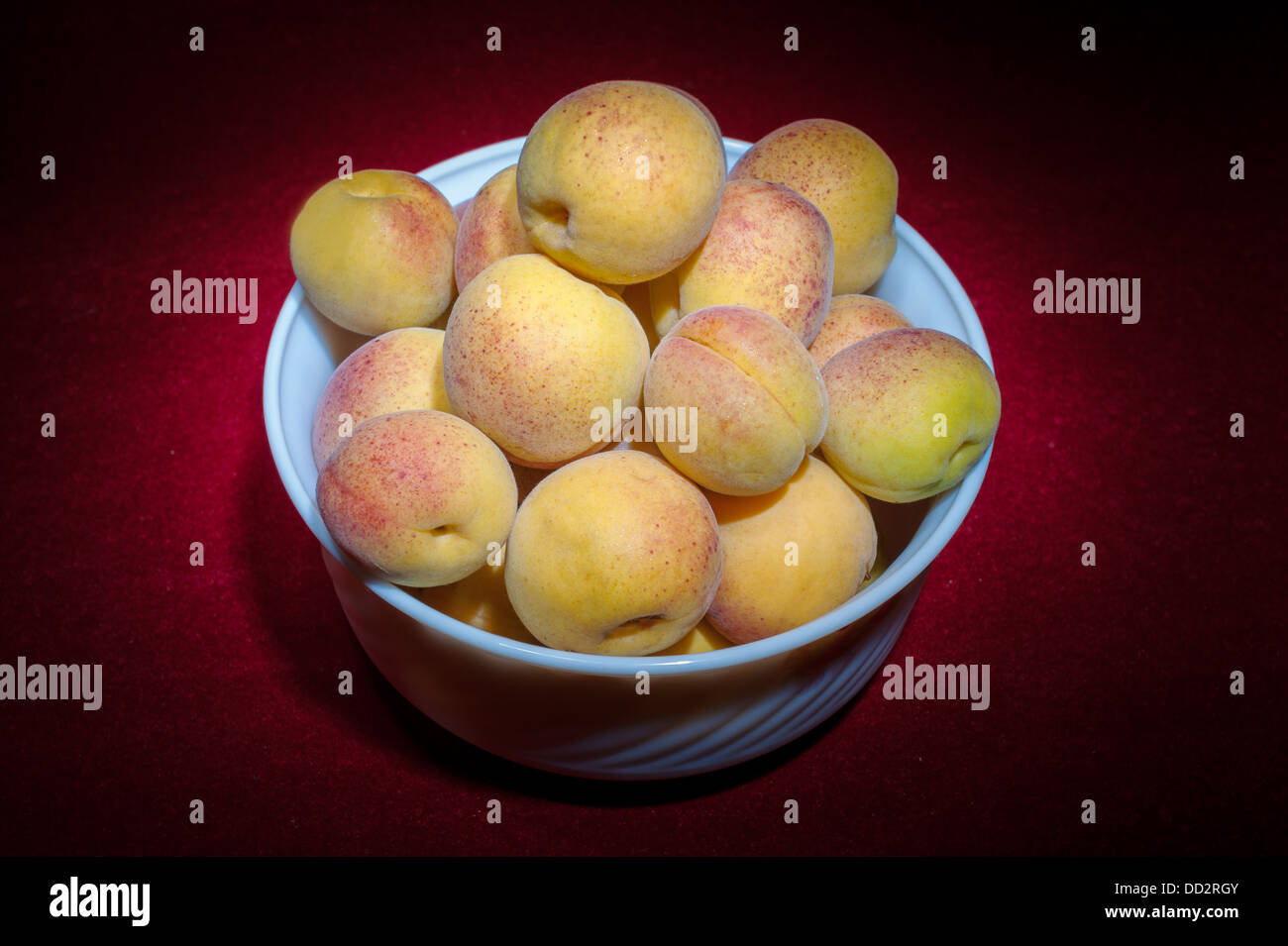 Apricots on dark red background Stock Photo - Alamy