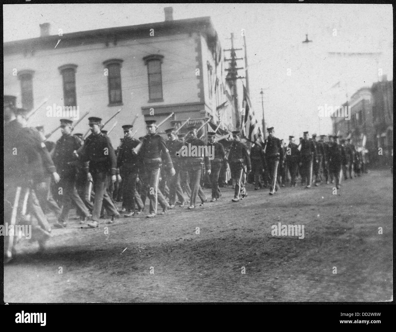 A photograph of men with rifles marching in a parade, likely during a ...
