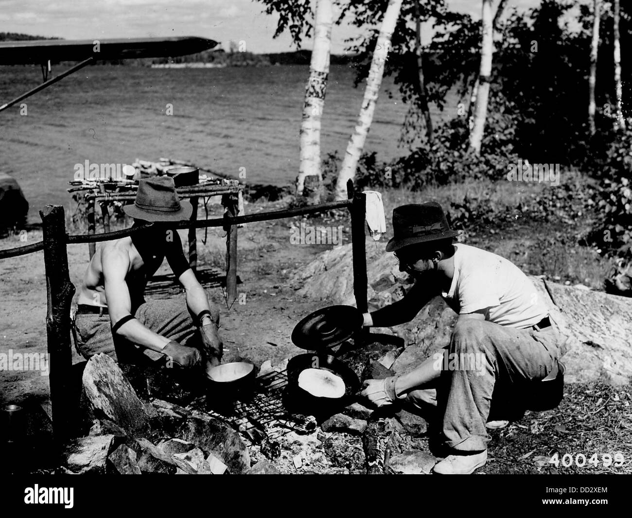 A canoeist prepares lunch at a campsite, reflecting outdoor living and ...