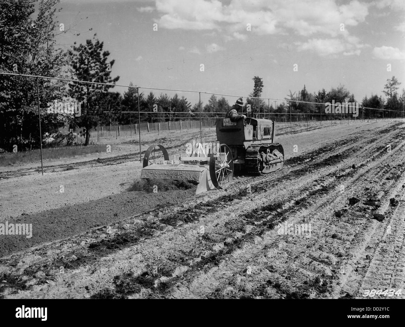 A rototiller is in operation, likely in a farm field or garden, where ...