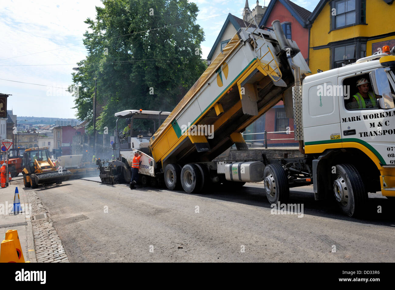 Road works, asphalt spreading machine being loaded with asphalt from ...