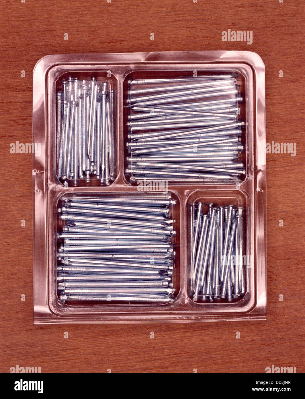A plastic package with metal nails in compartments. Wooden background ...