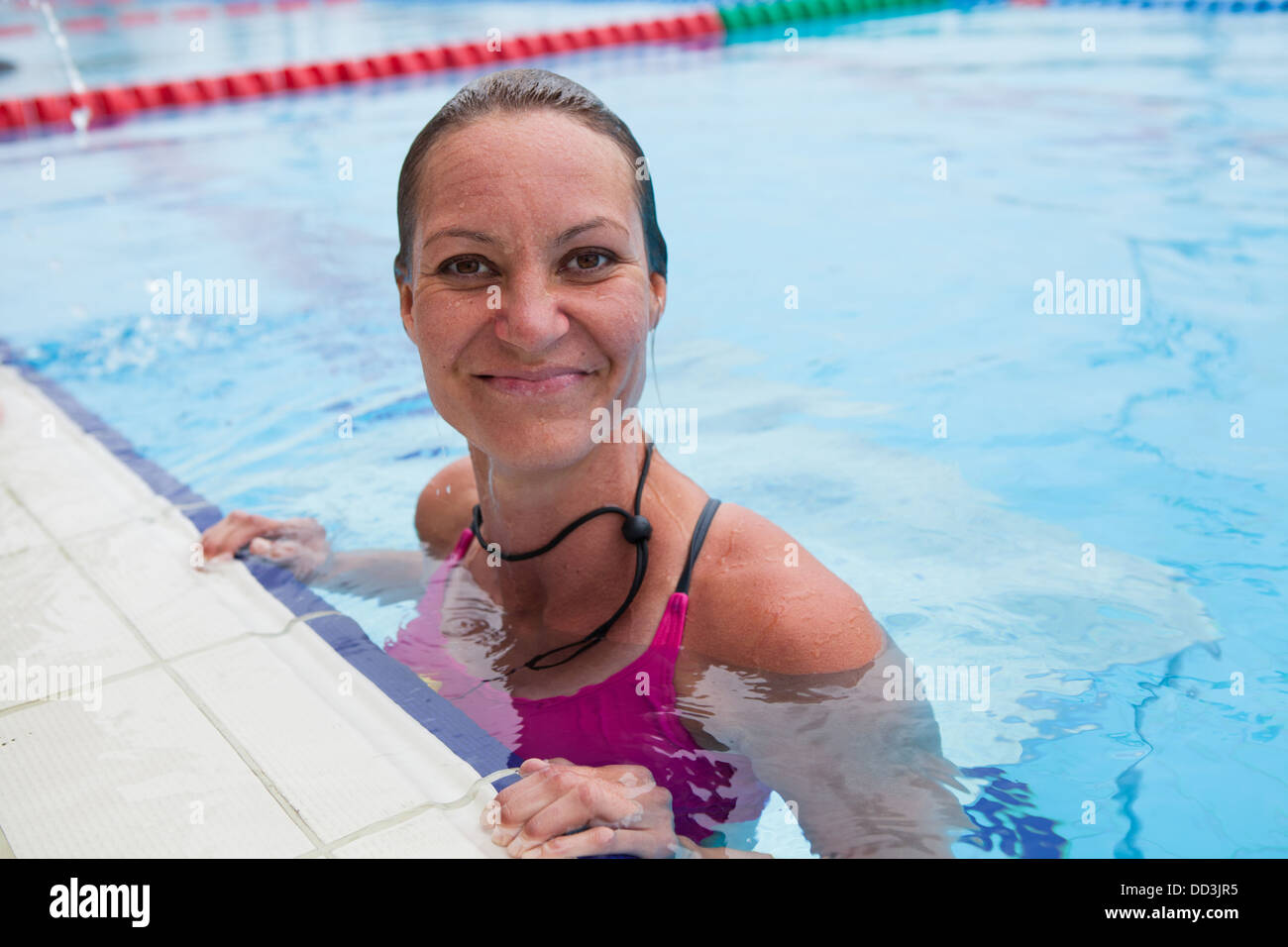 Smiling female swimmer resting at edge of outdoor swimming pool Stock ...