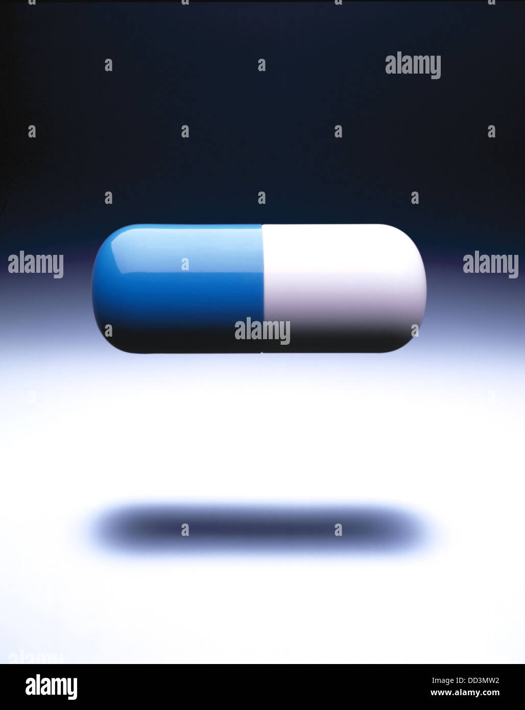 A blue and white medical capsule pill floating above a white surface. A ...