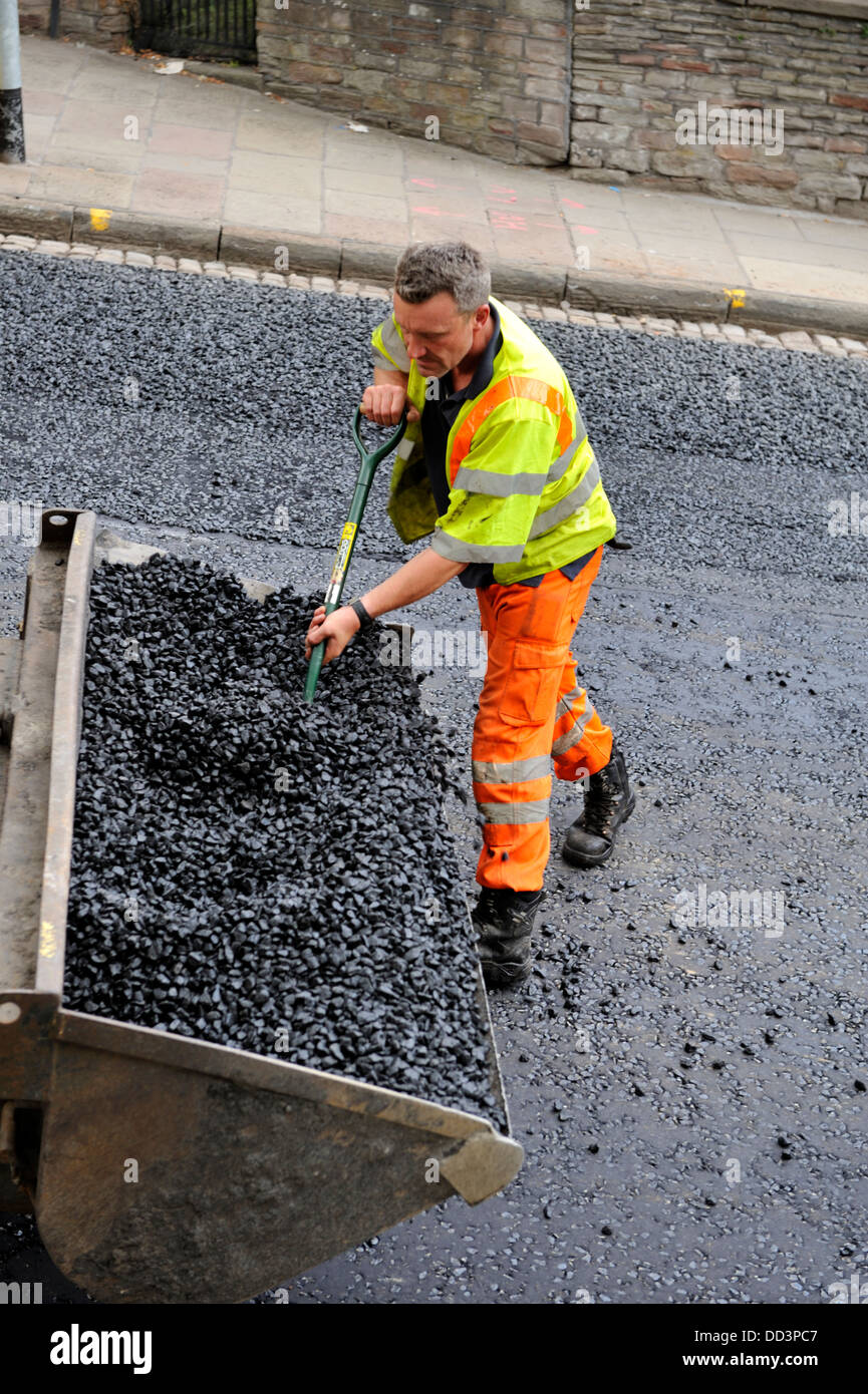 Workman collecting asphalt from front loader bucket for spreading ...
