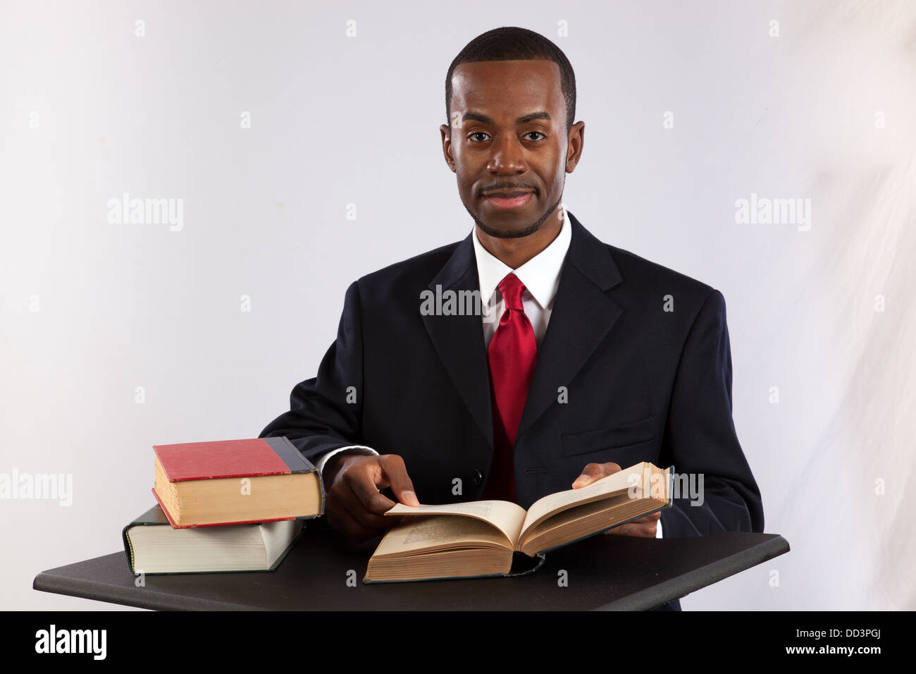 Handsome black businessman in a dark suit and red tie, studying an open ...