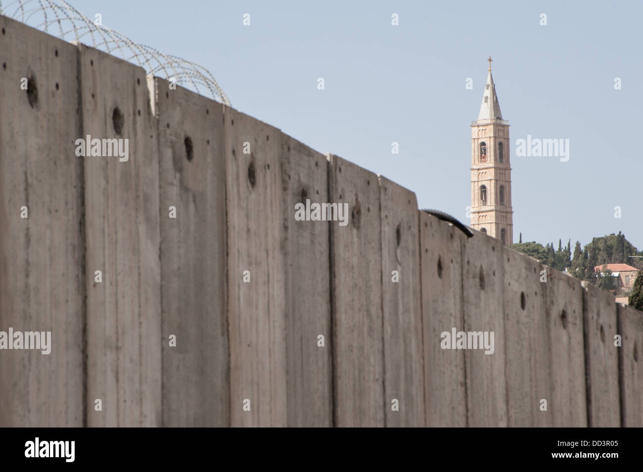 A church tower rises above the Israeli separation wall that divides ...