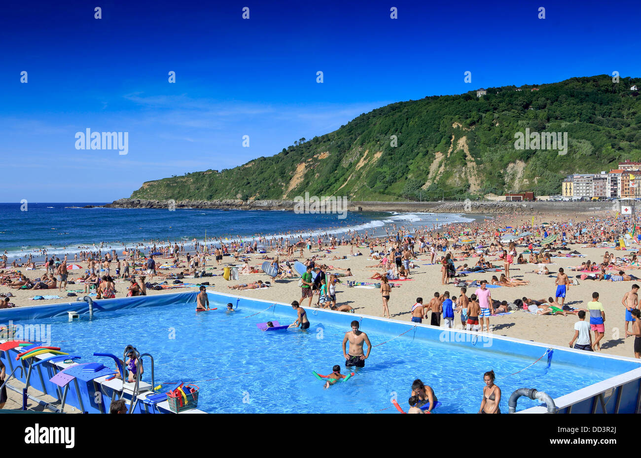 Swimming pool in use on a crowded Gros Beach during mid summer in San ...