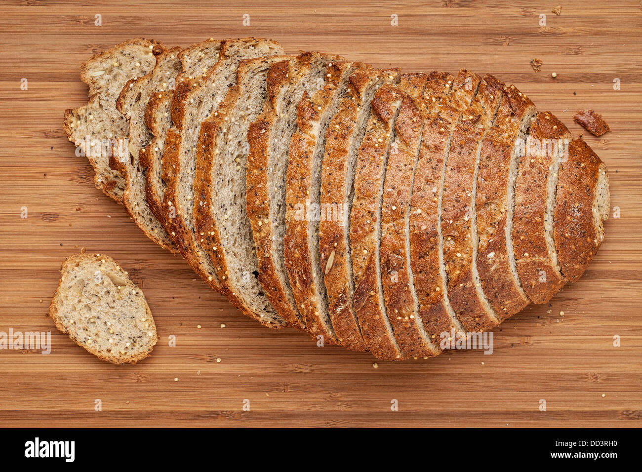 a small sliced loaf of bread with whole wheat grain and seeds on bamboo ...